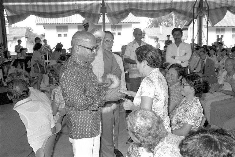 President C V Devan Nair distributing red packets to