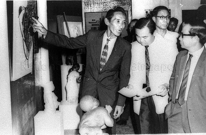 LIM NANG SENG (LEFT) SHOWING HIS METAL WORKS SCULPTURE TO