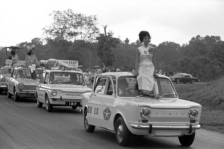 A motorcade with models sitting on the top of the cars