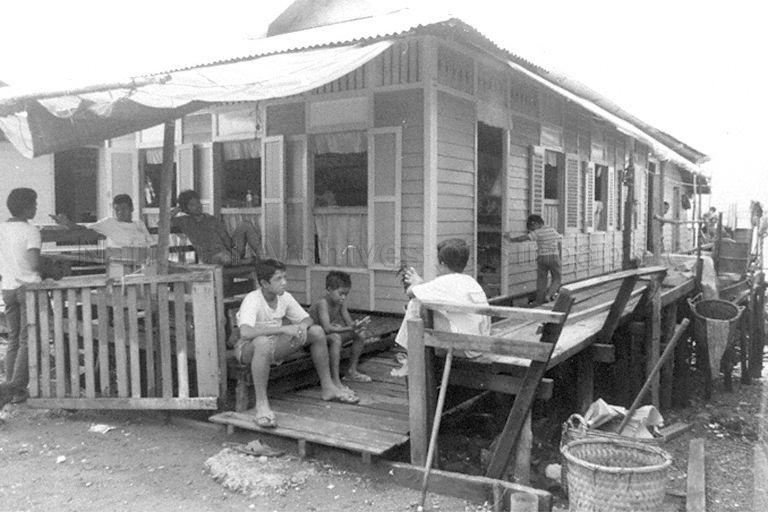 Young men and boys outside a Malay kampong house built on