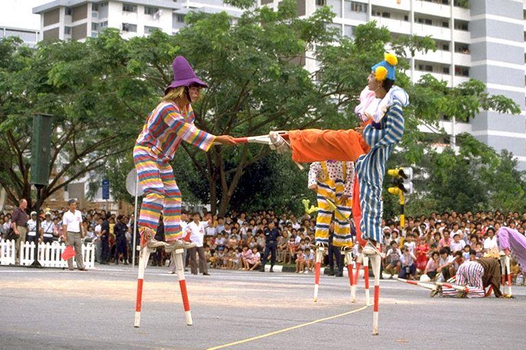 Stilt walkers with painted faces and in garishly coloured