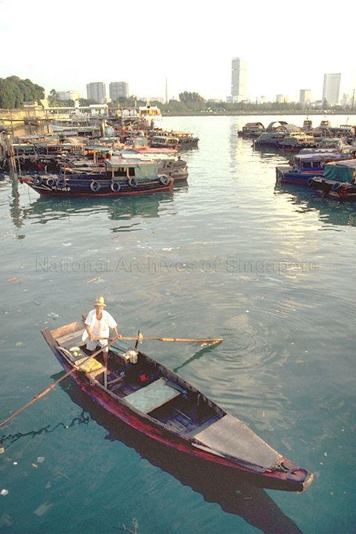A BOAT-ROWER ROWING HIS SAMPAN ALONG THE SINGAPORE RIVER