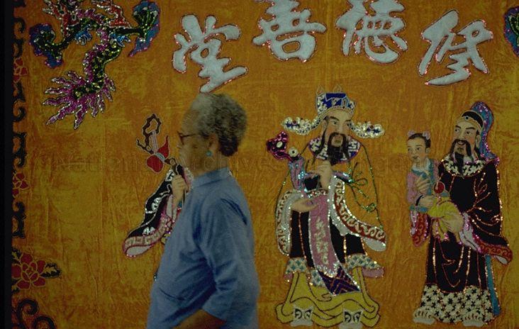 SAM FOO DRESSED WOMAN WALKS PAST WAYANG STAGE AND SEQUINED