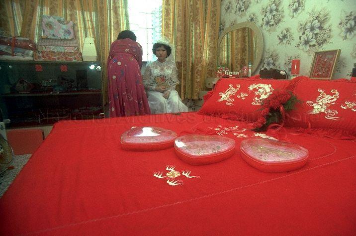CHINESE WEDDING -- BRIDE WITH BOUQUET POSES BY RED SHEETED