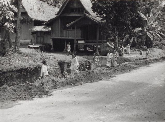 View of children outside traditional attap house in Malacca