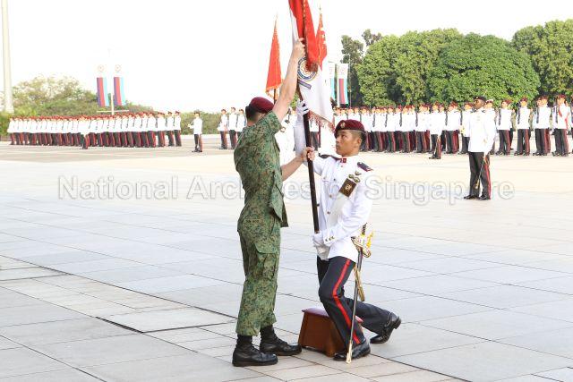 An award recipient with the State Colours at Singapore Armed