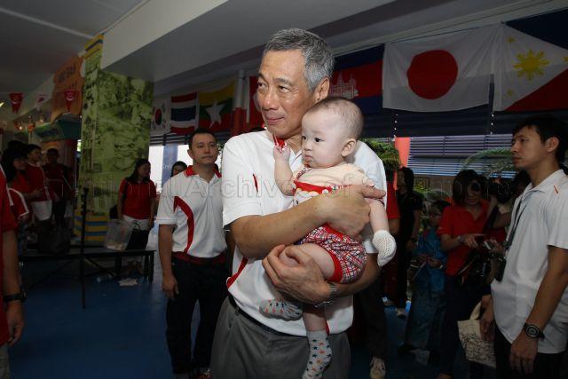 Prime Minister Lee Hsien Loong is holding a baby at National