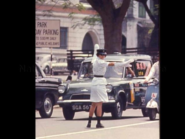 Photograph of a female traffic police directing traffic.