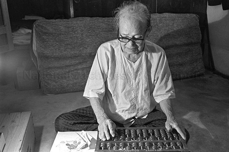 AN OLD LADY DOING HER CALCULATIONS WITH THE CHINESE ABACUS