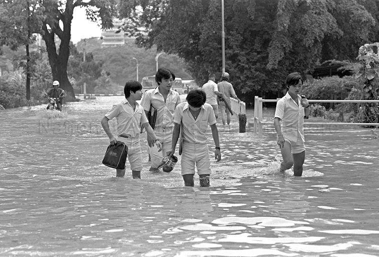STUDENTS WADING THROUGH THE FLOODED STREETS. FLOOD WATERS